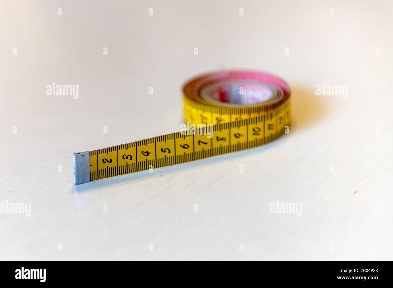 yellow tape measure on a white background Stock Photo - Alamy