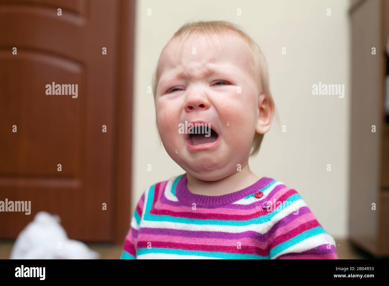 Portrait of crying baby girl in pink dress Stock Photo - Alamy