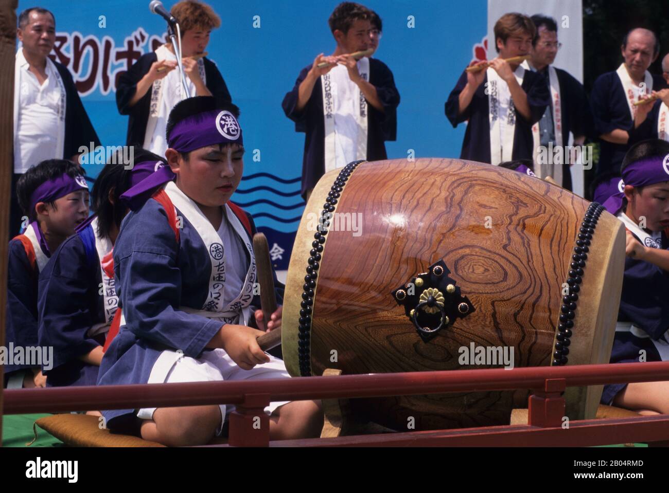 Japanese teenage boy playing a traditional Taiko drum during a farmer’s ...