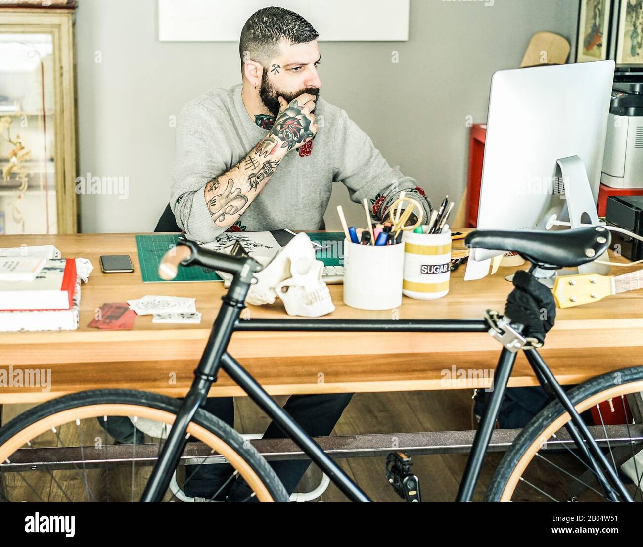 Tattoo artist using computer inside ink studio - Hipster tattoer ...