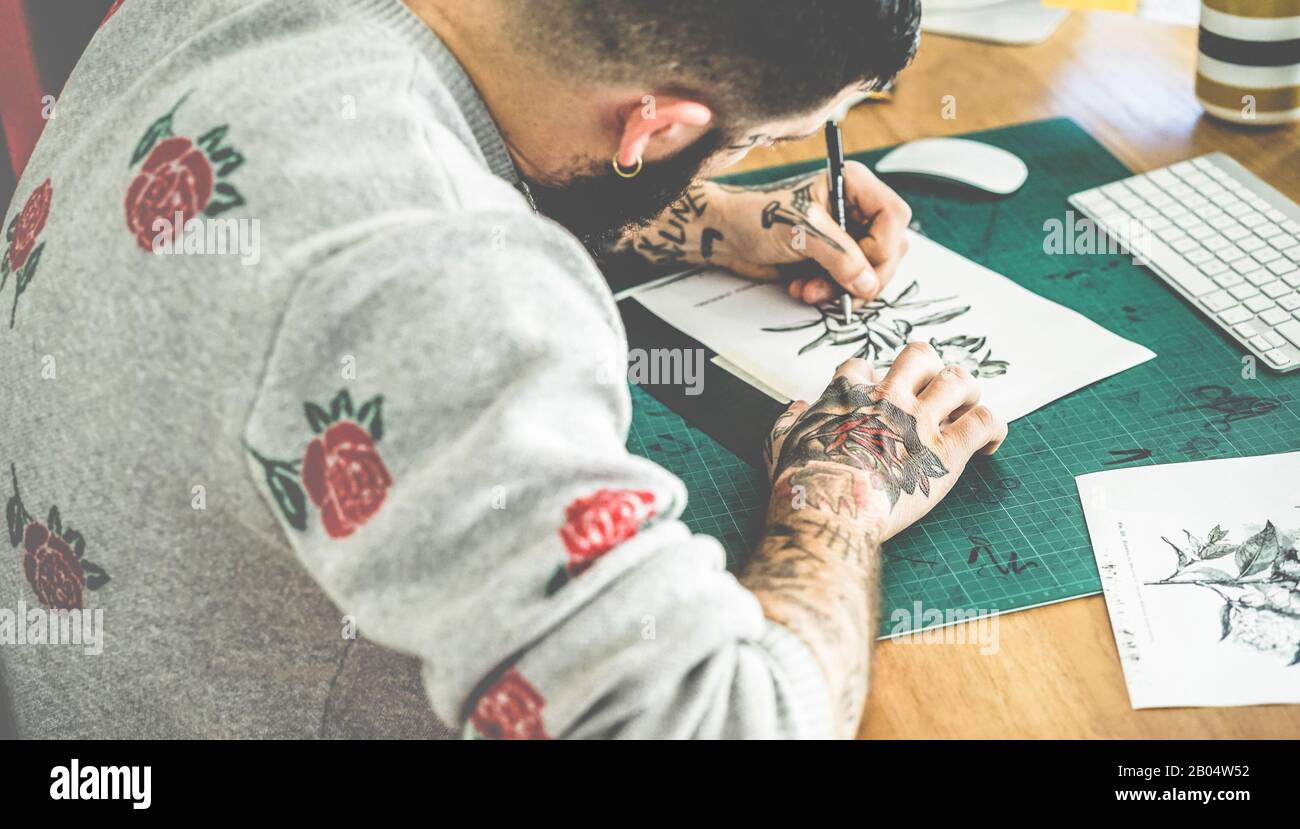 Young tattoo artist drawing sketch inside ink studio - Hipster tattoer ...