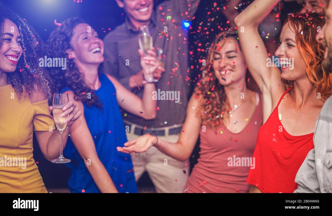 Happy friends making party throwing confetti, dancing and drinking ...