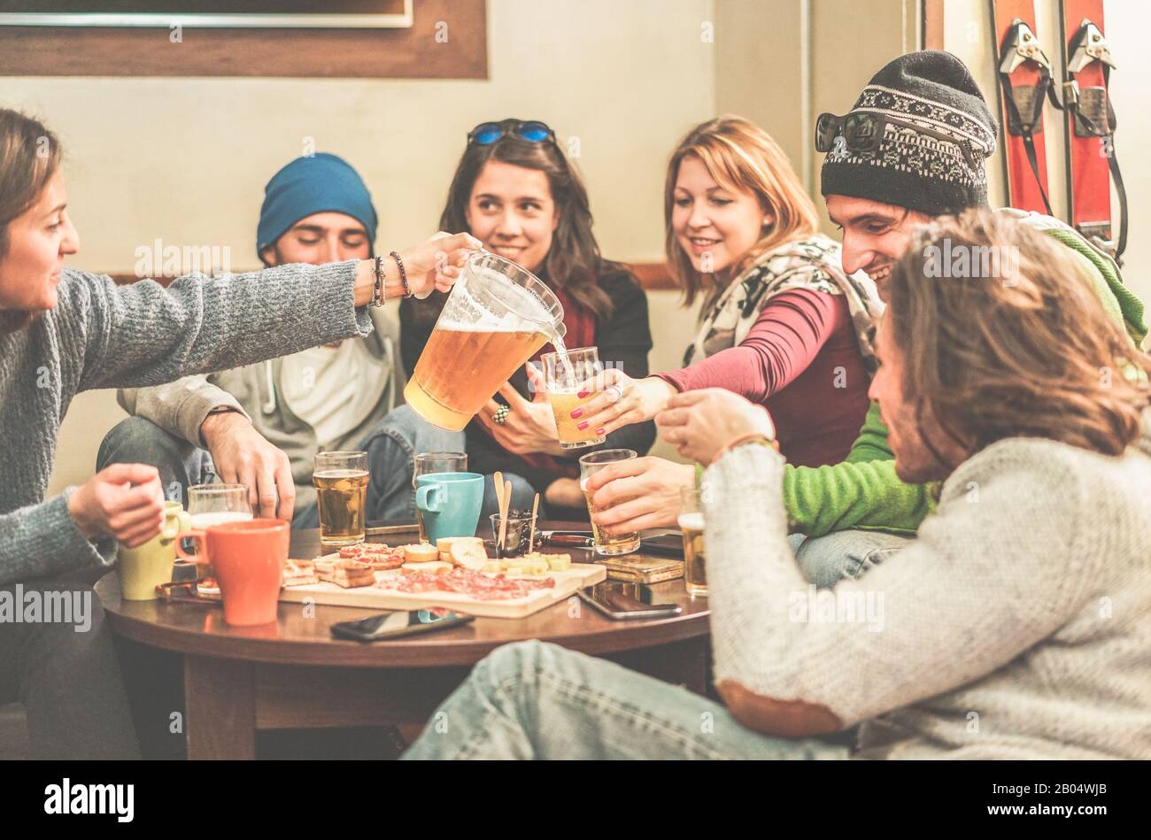 Happy friends drinking beer doing appetizer at chalet pub in mountains ...