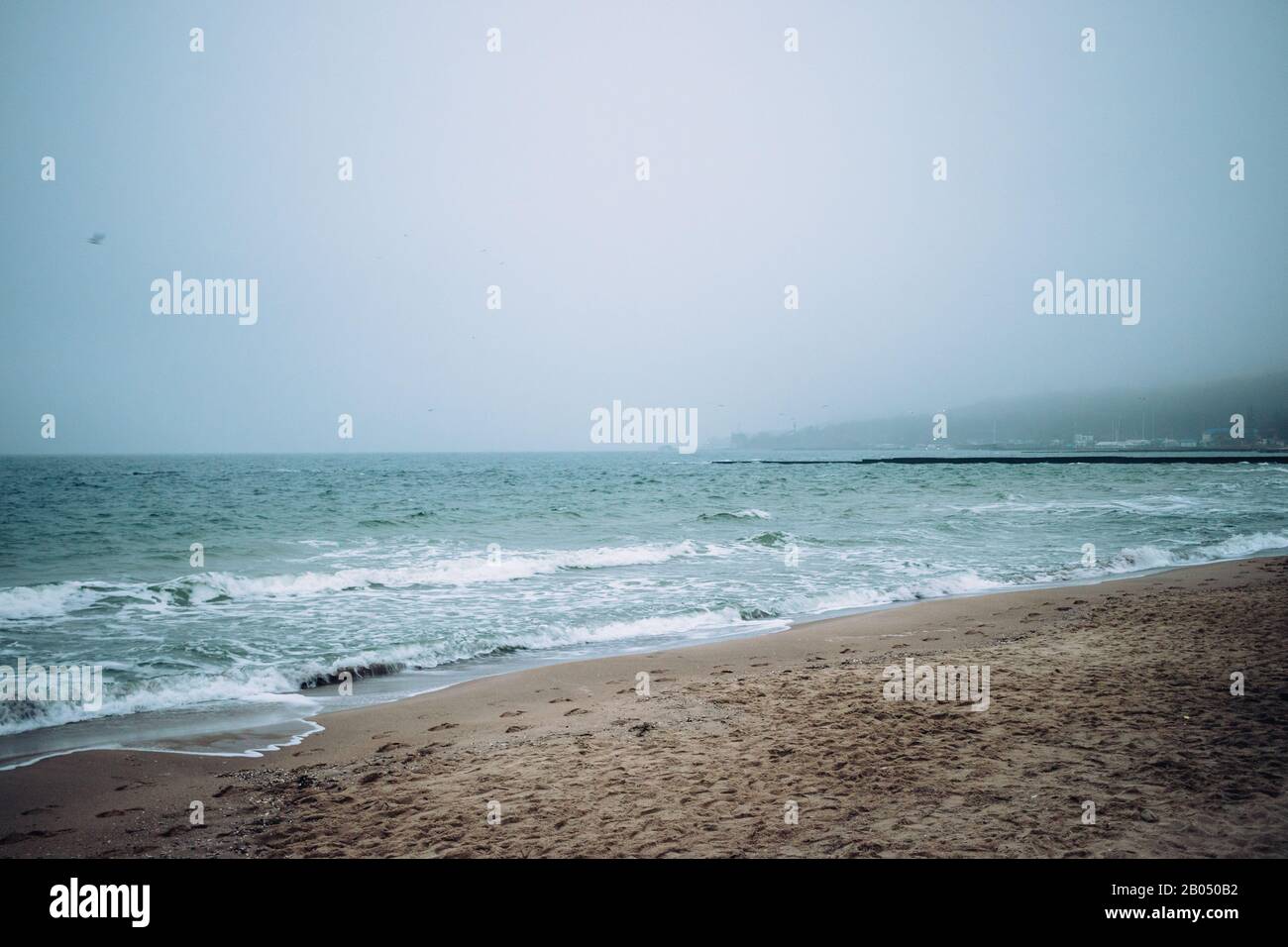 Sandy sea coast in city at evening in cold foggy weather Stock Photo ...