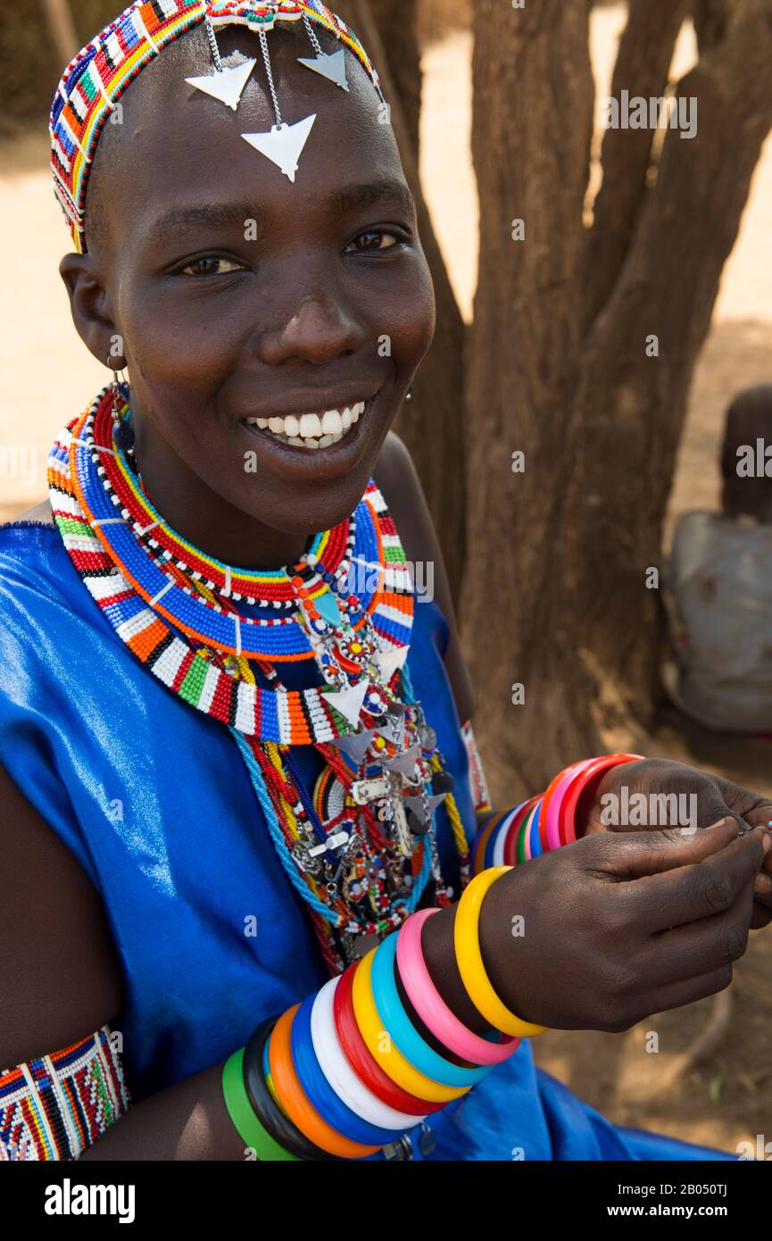 Village scene with Masai women making glass bead jewelry in a Masai ...