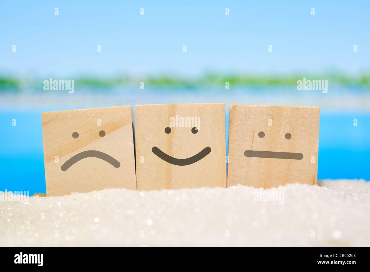 Abstract rating of emoticons in the sand against a blurred sea with a ...