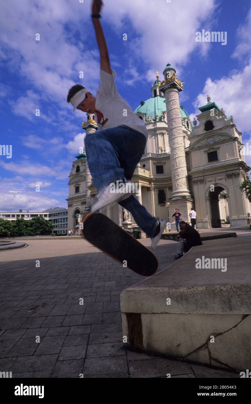 A teenage boy is skateboarding in front of the Karlskirche (Baroque ...
