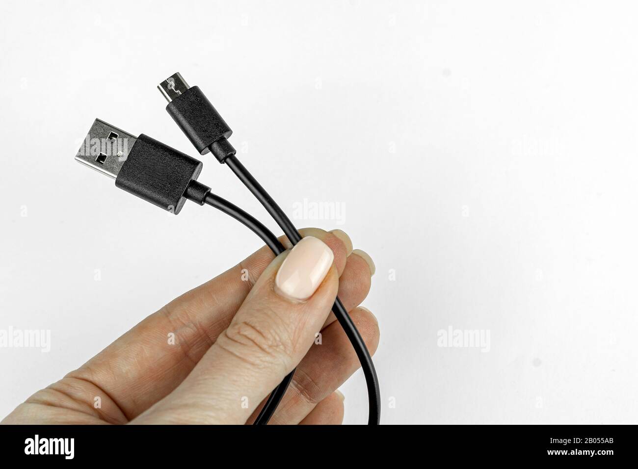 Hand holding usb to micro usb cable on white background copy space ...
