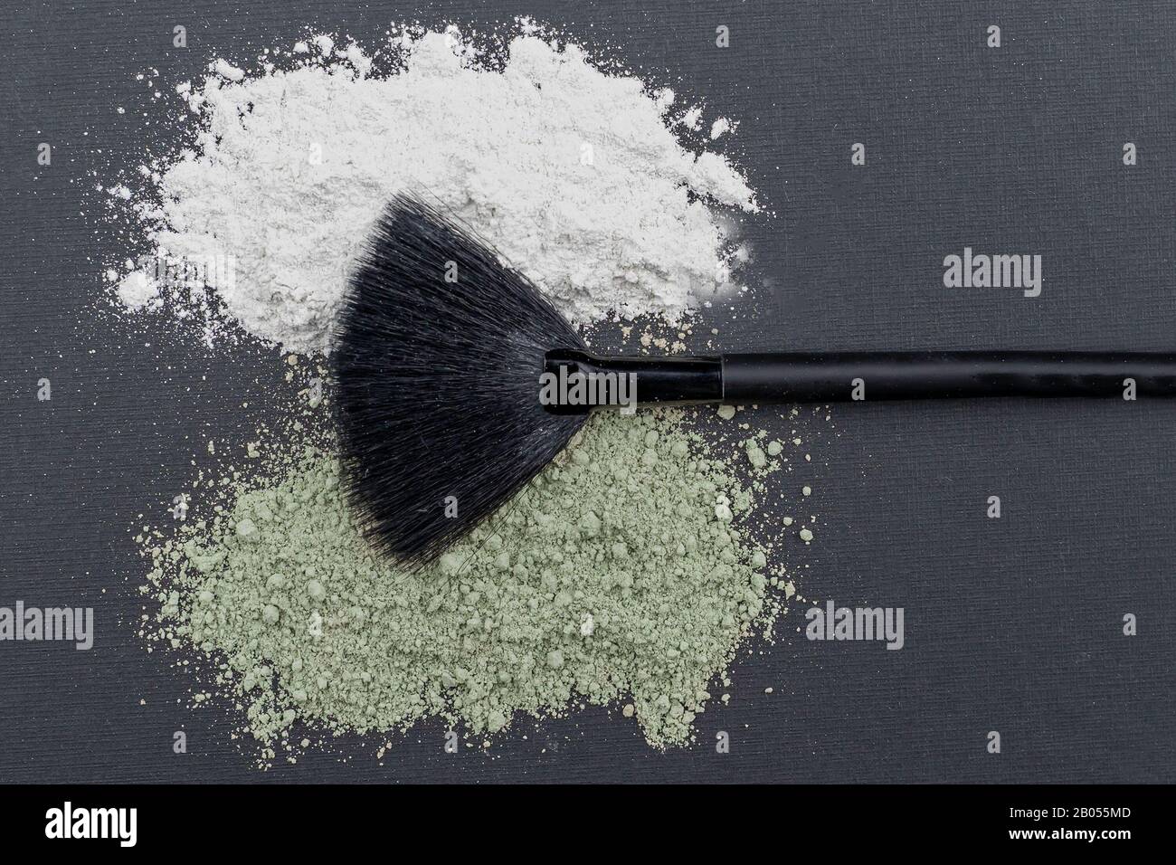 Close-up of a cosmetic dry white and green clay powder on gray ...