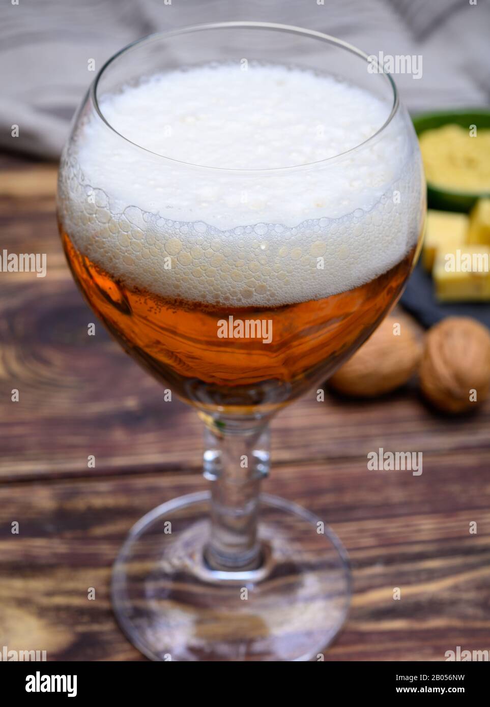 Glass of Belgian abbey blond beer and stone plate with cheeses made by ...