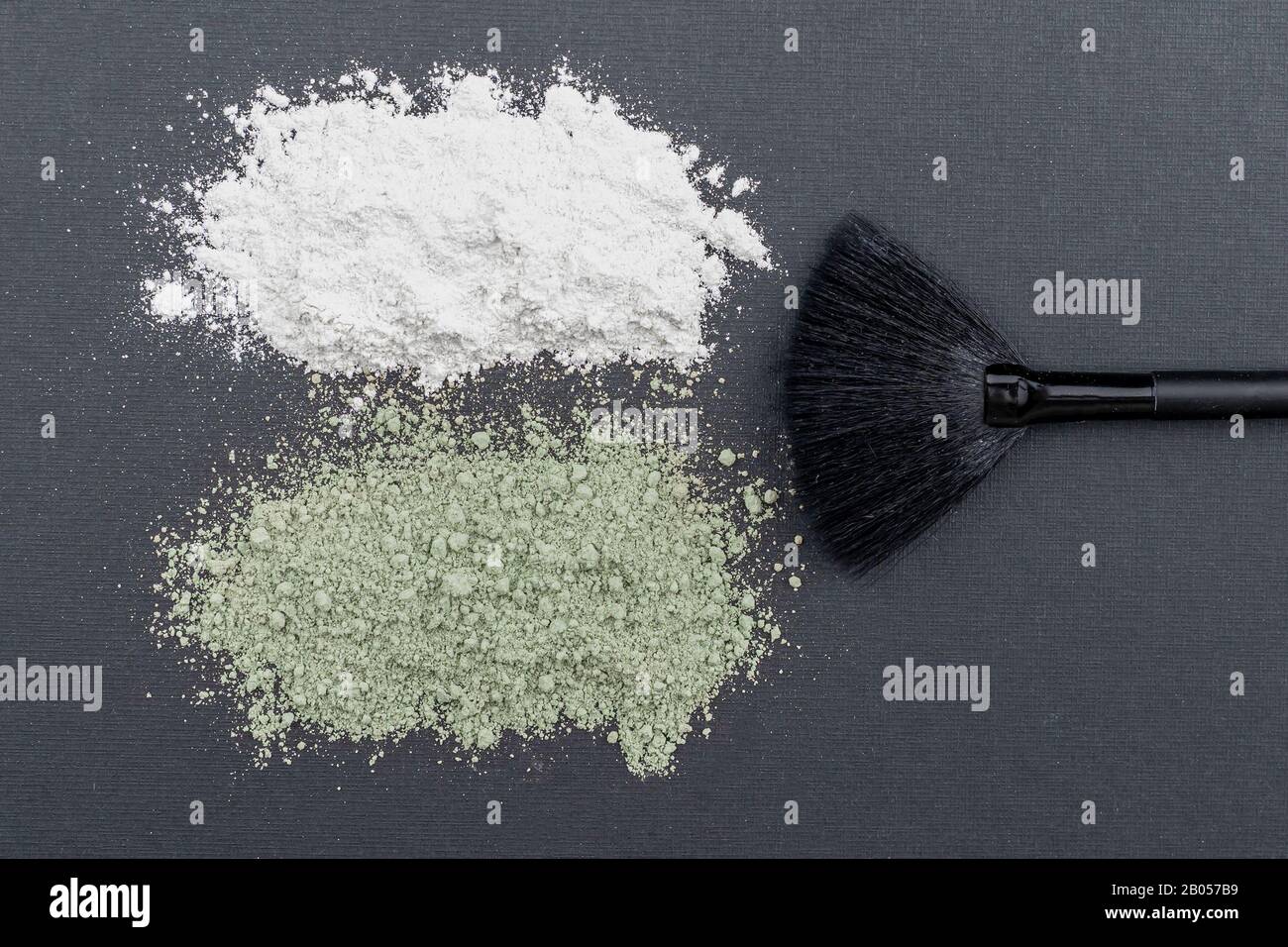 Close-up of a cosmetic dry white and green clay powder on gray ...