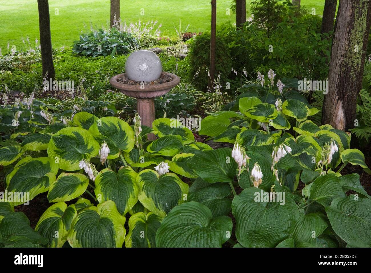 Pedestal planter filled with rocks and globe shaped stone sculpture ...