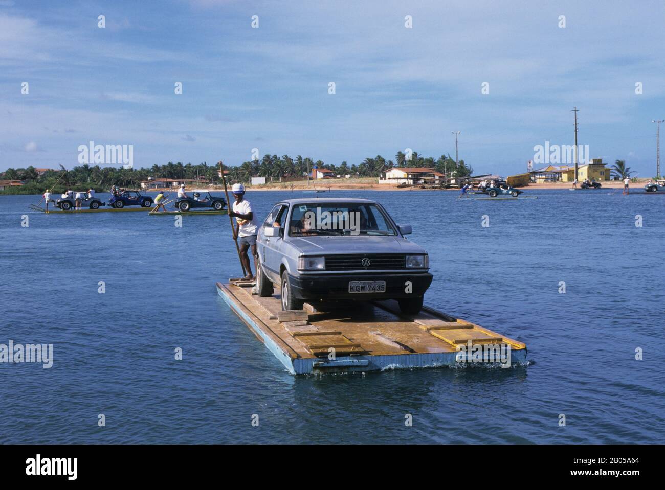 A small hand powered ferry is transporting one car across a bay near ...