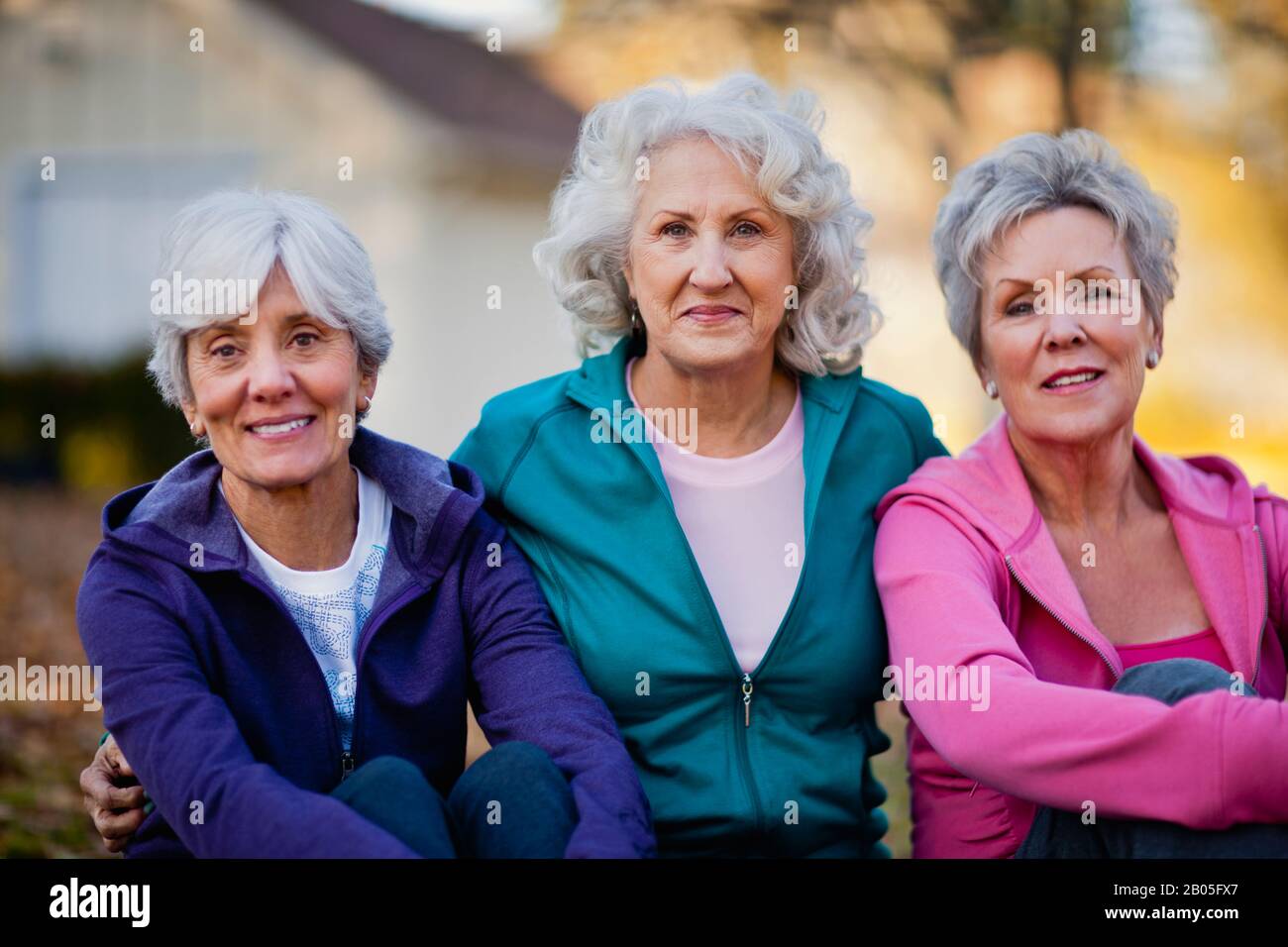 Portrait of three smiling women with arms around each other Stock Photo ...