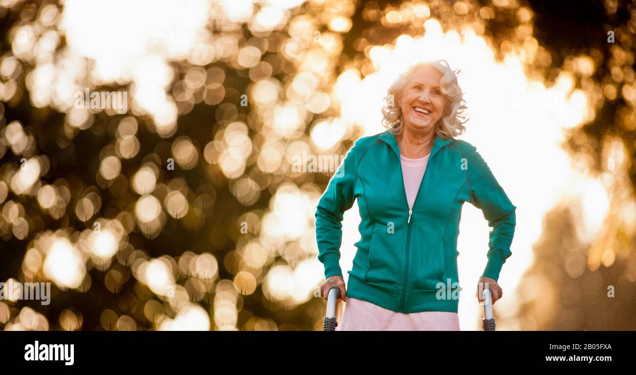Active senior woman walking with a walking frame in a park Stock Photo ...