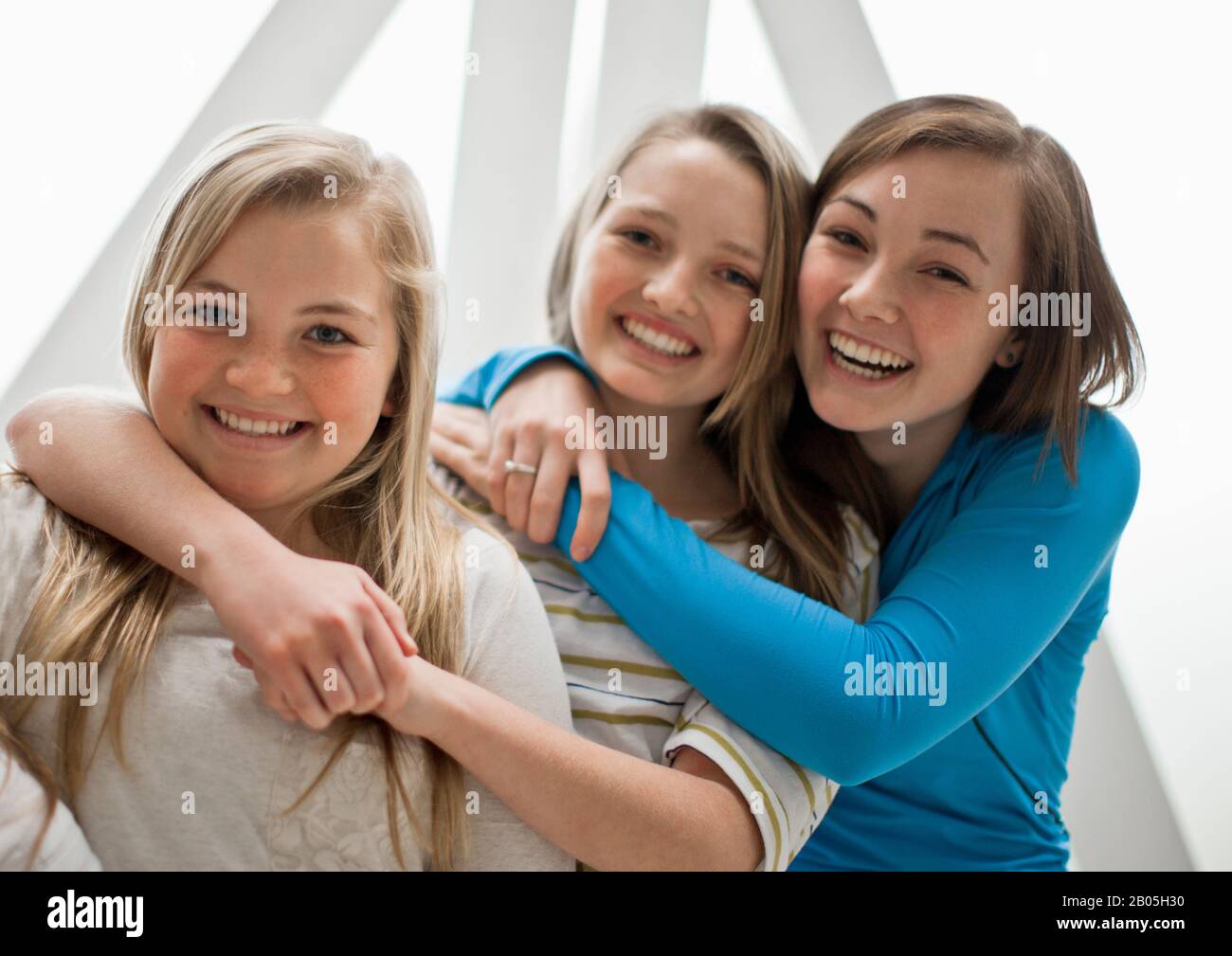 Portrait of three smiling teenage girls standing side by side with ...