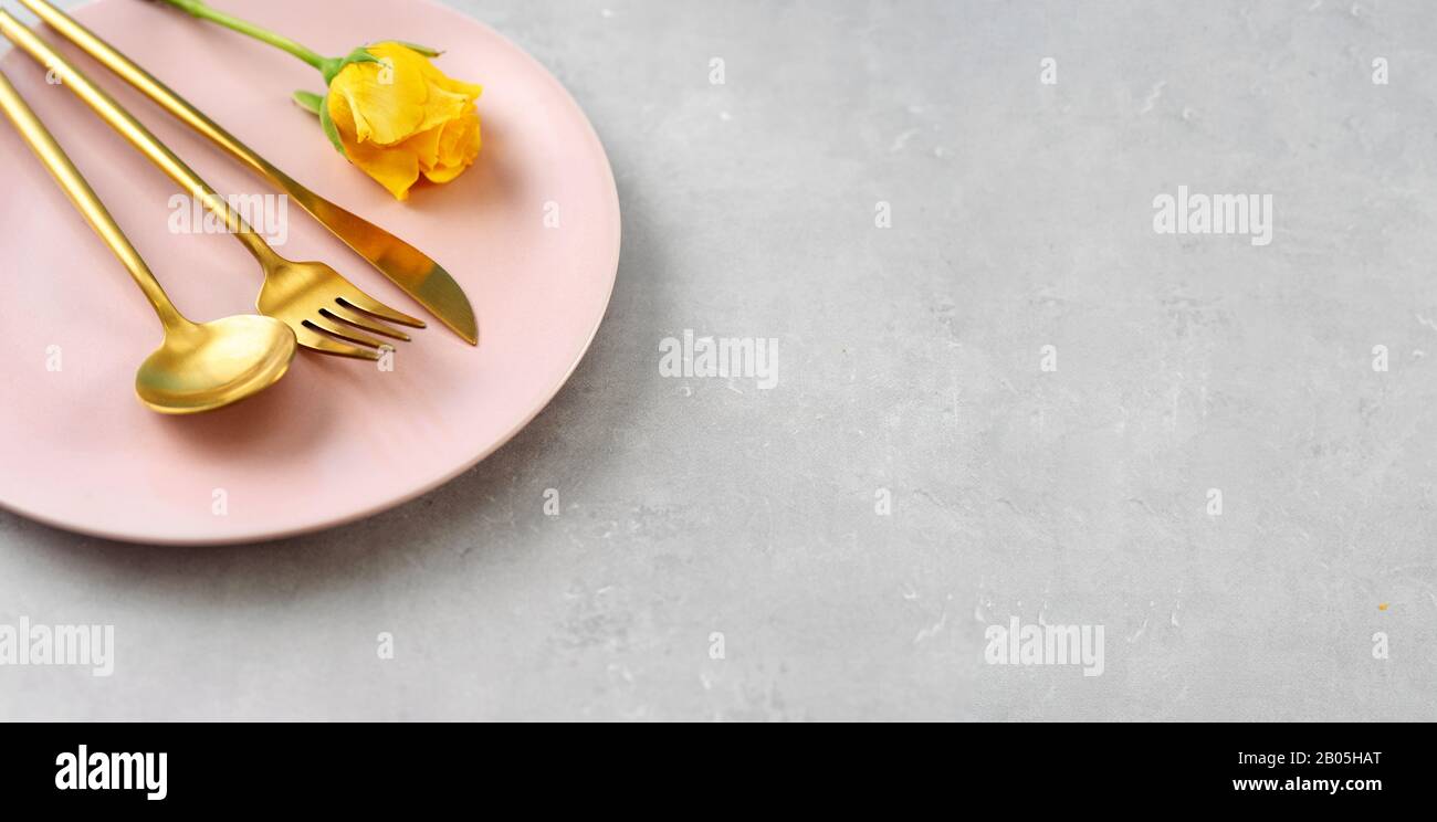 Top view of pink plate and gold cutlery on grey background Stock Photo ...