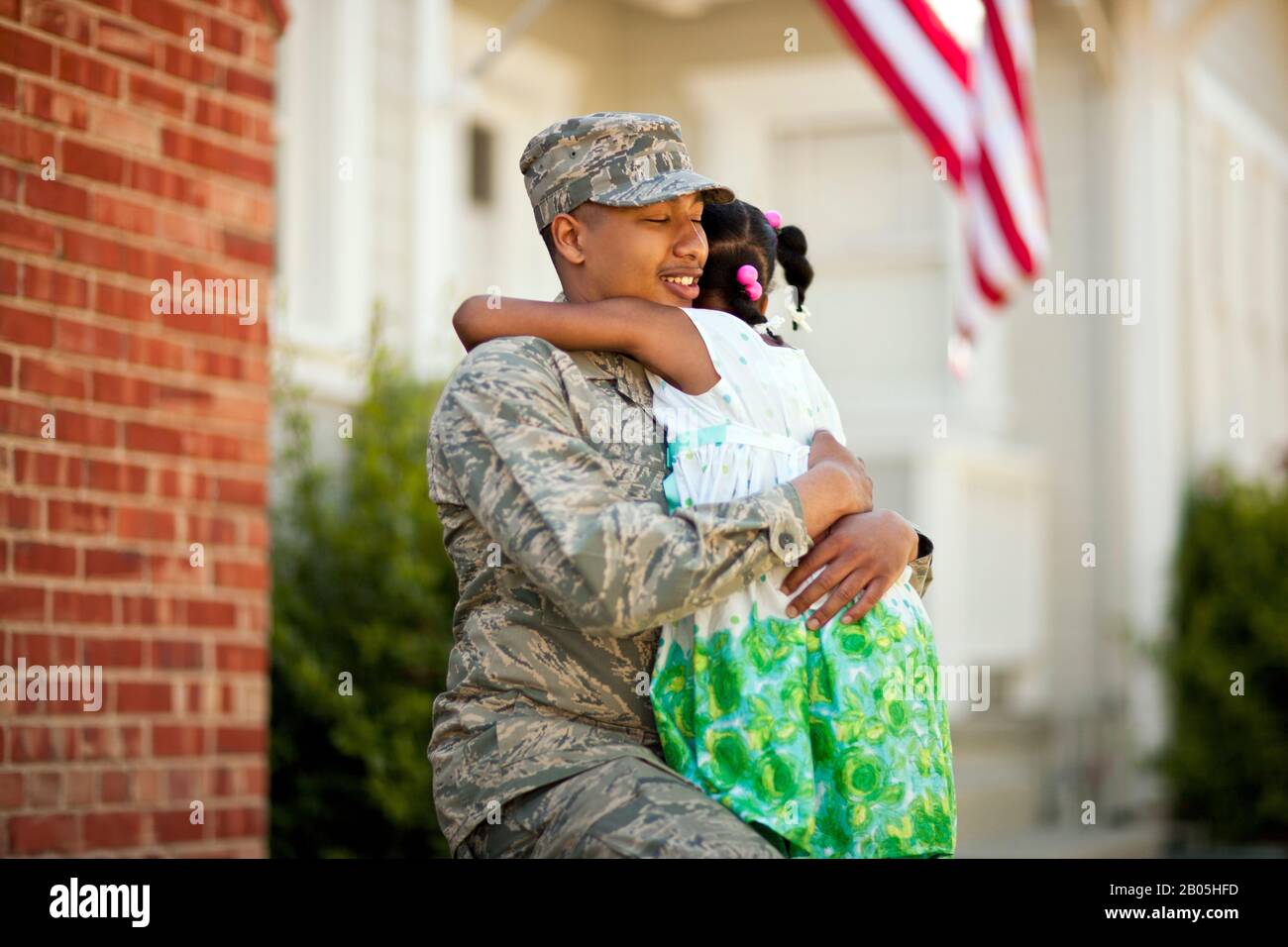 Smiling young man hugging his young daughter outside their home Stock ...