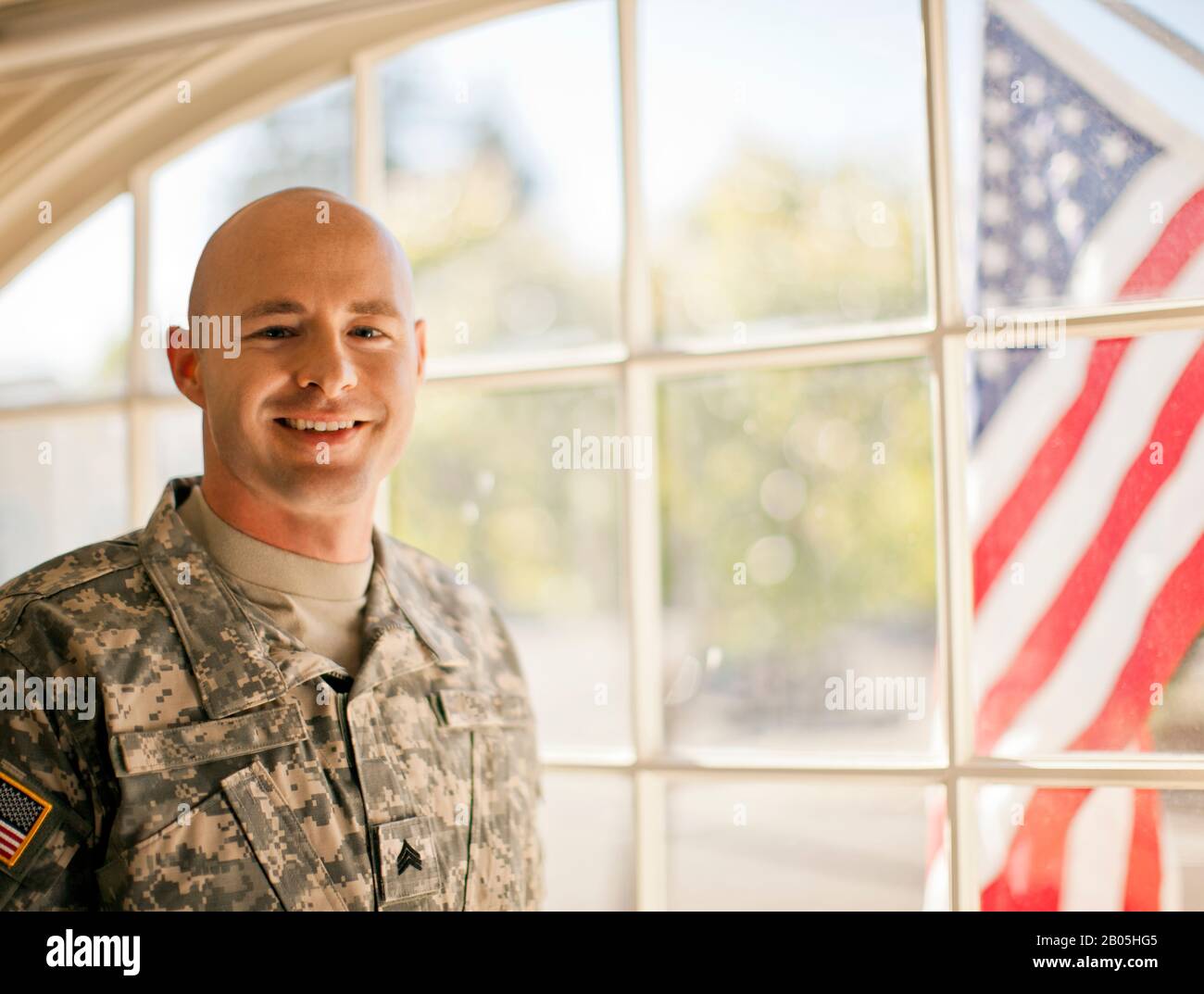 Portrait of a smiling male soldier standing next to a window inside his ...