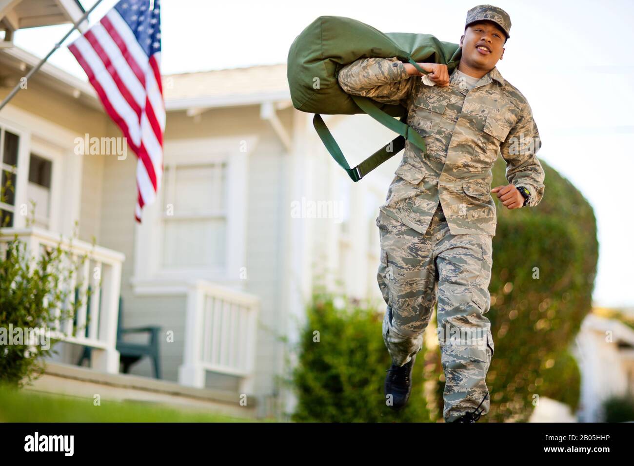 Portrait of a smiling soldier carrying a bag over his shoulder while ...