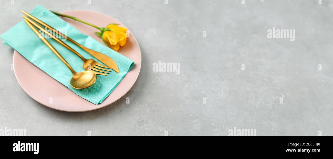 Top view of pink plate and gold cutlery on grey background Stock Photo ...