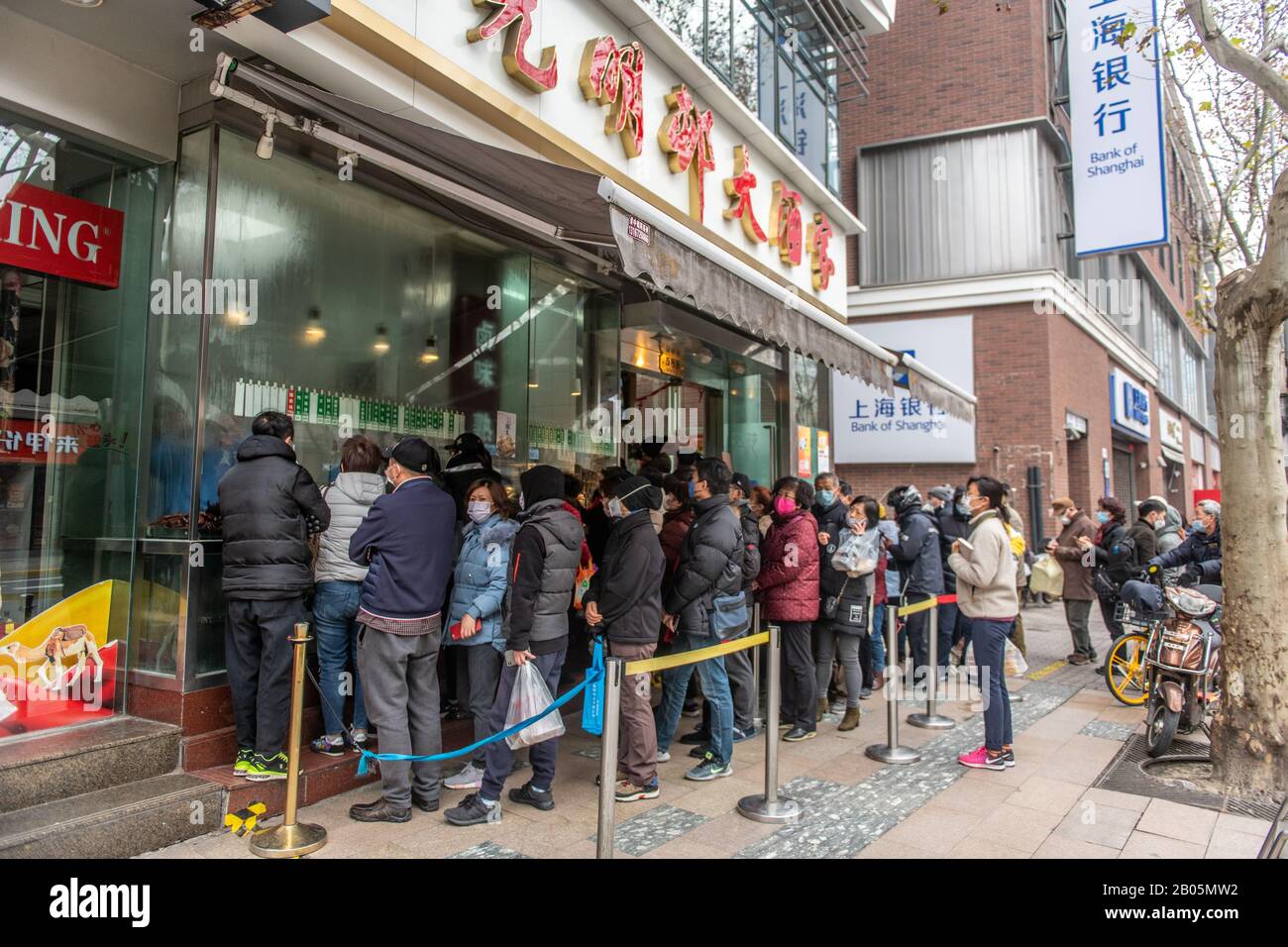 People standing in a crowd on the sidewalk outside of a a shop in ...