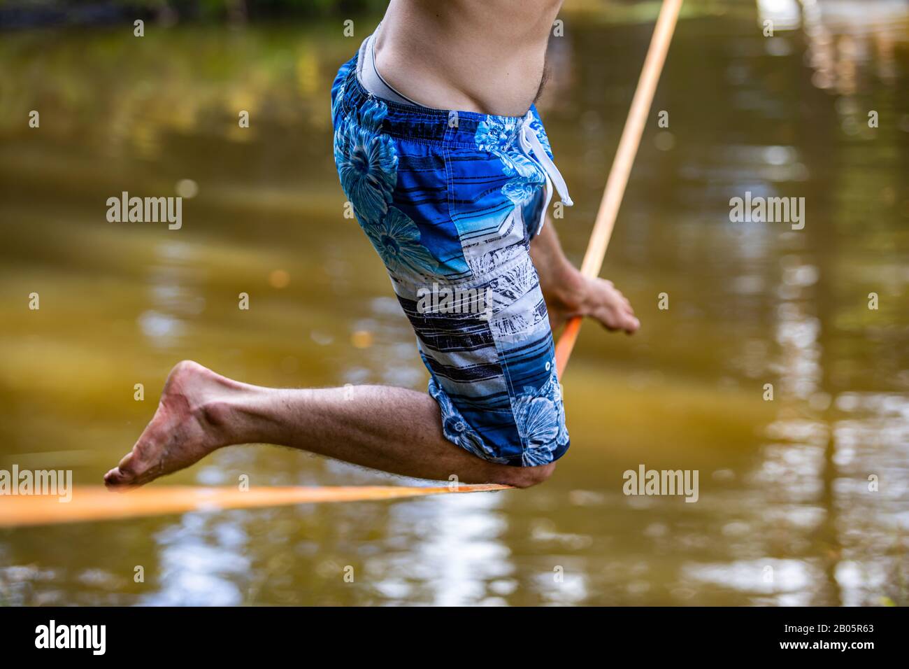 A young man risks getting wet in a lake as he performs slack wire ...