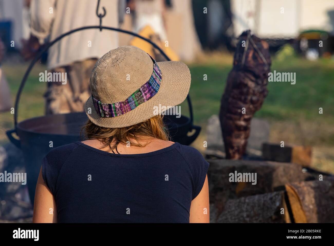 A woman wearing a brimmed hessian hat is seen from the back, sitting by ...