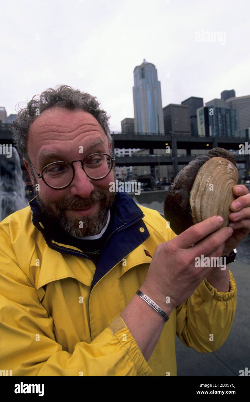 USA, WASHINGTON, SEATTLE, DAVID GORDON WITH GEODUCK, SEATTLE SKYLINE IN ...