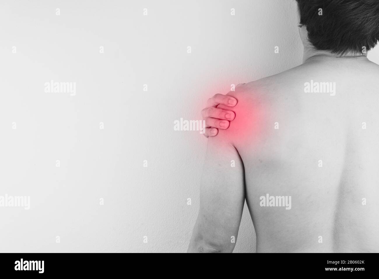 Black and white closeup man suffering from shoulder pain with red spot ...
