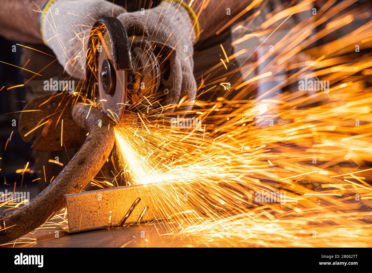 A close-up of a car mechanic using a metal grinder to cut a car silent ...
