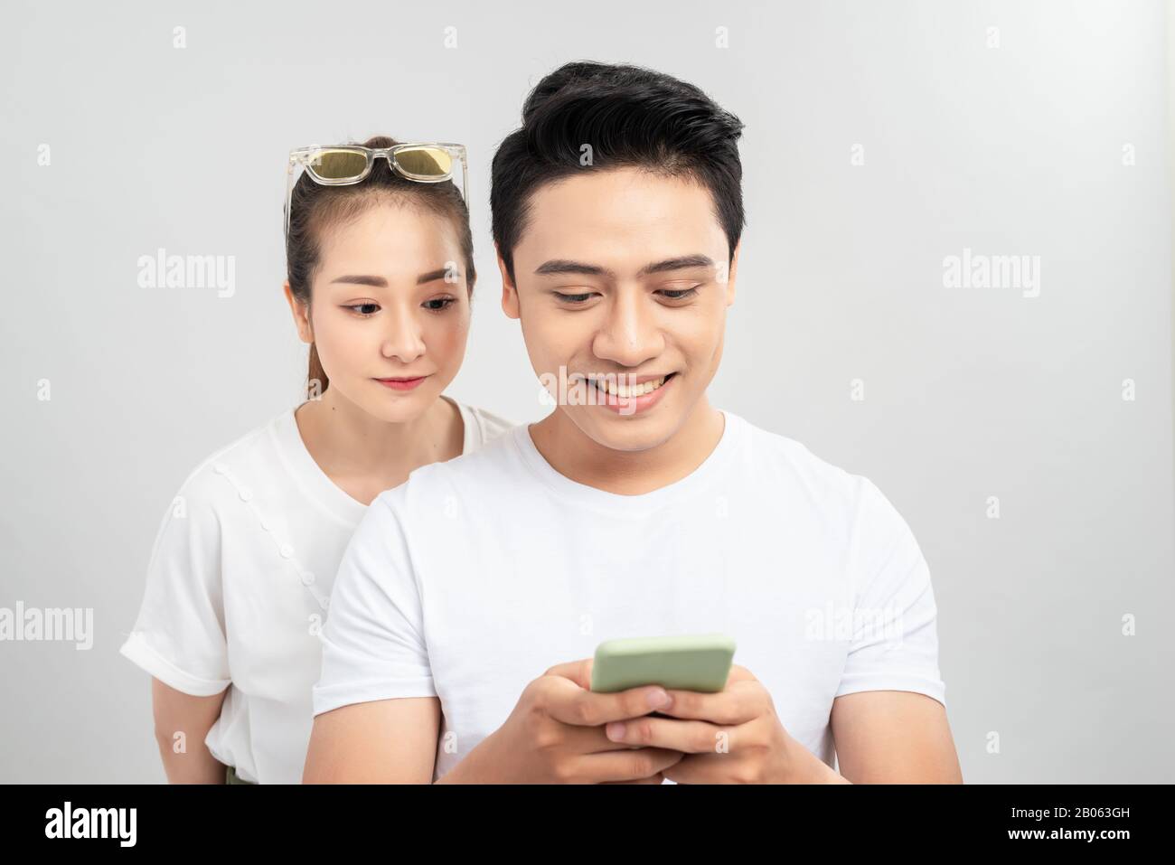 Attractive suspicious young couple standing isolated over white ...