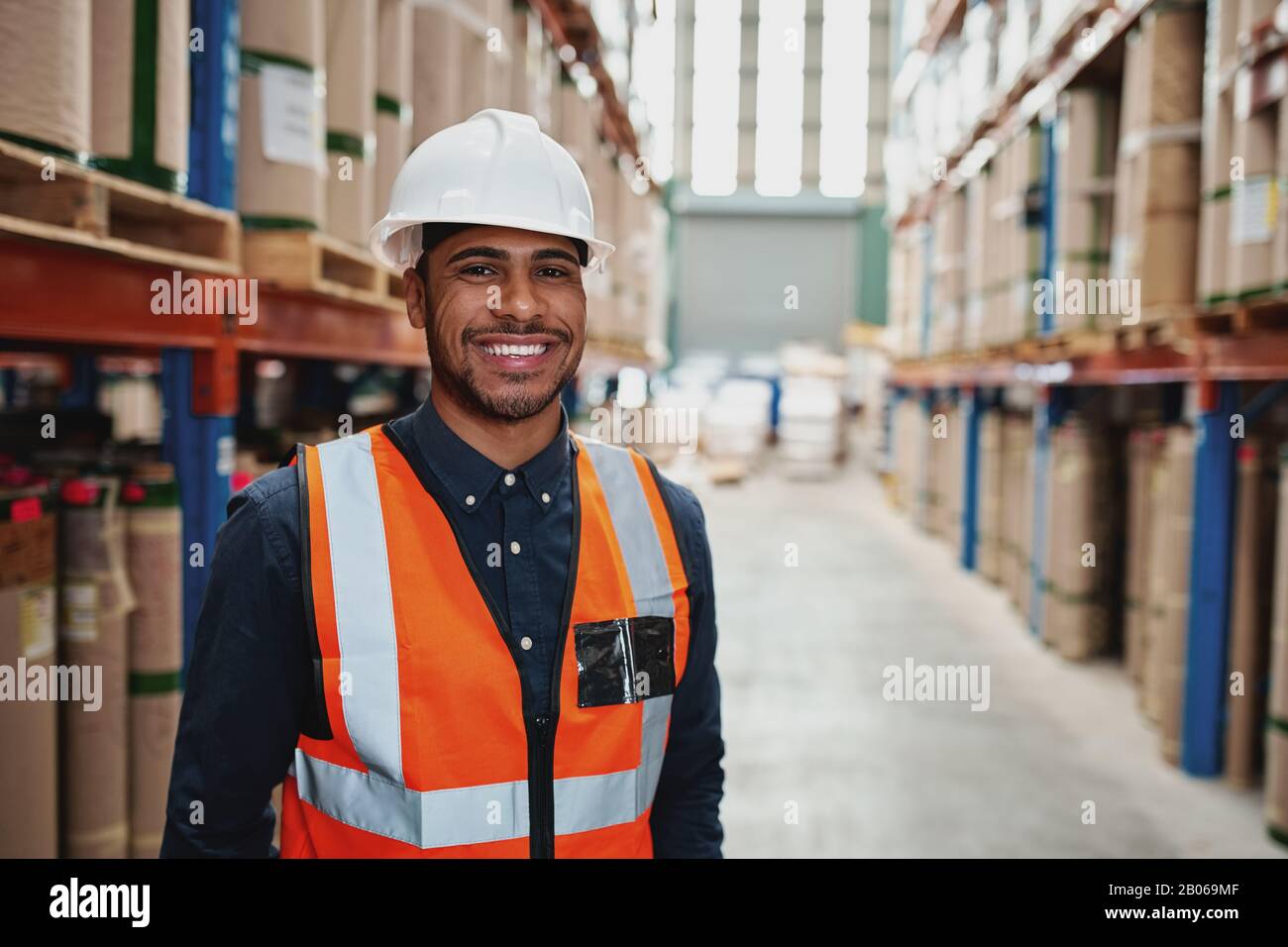 Happy male supervisor in warehouse standing in uniform with white ...