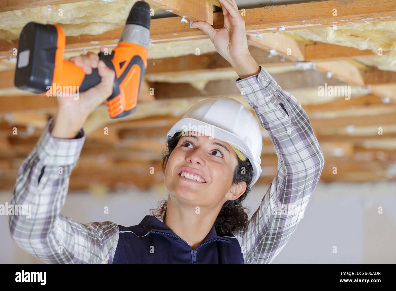 female builder using cordless drill overhead Stock Photo - Alamy