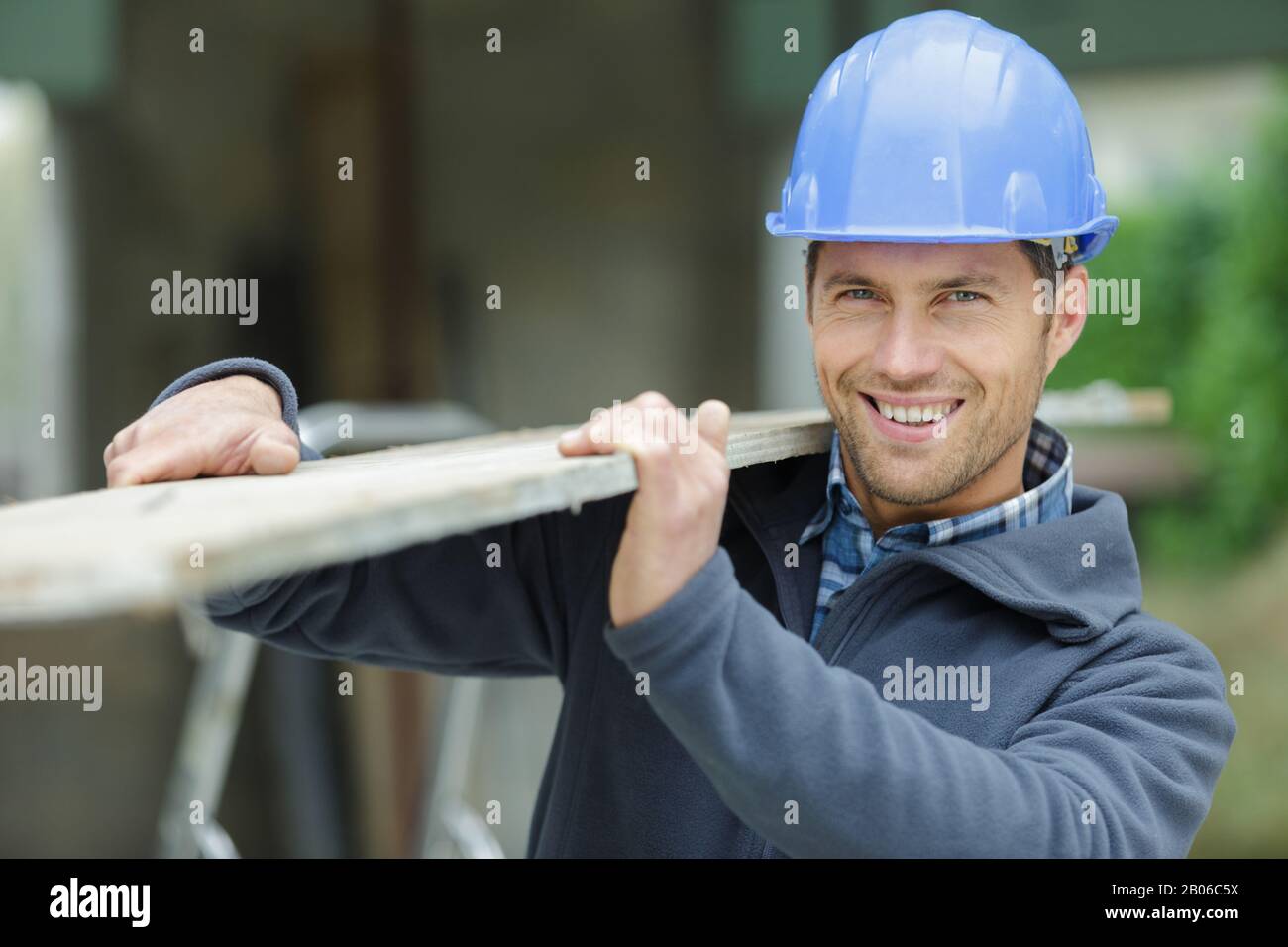 happy contractor in hard hat holding plank of wood Stock Photo - Alamy