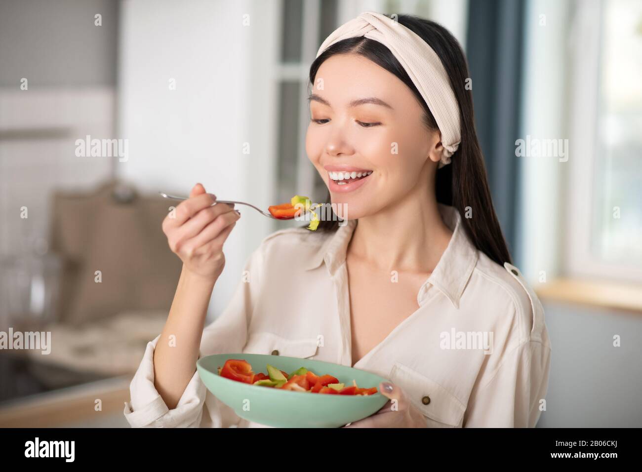 Beautiful joyful young lady eating vegetable salad Stock Photo - Alamy