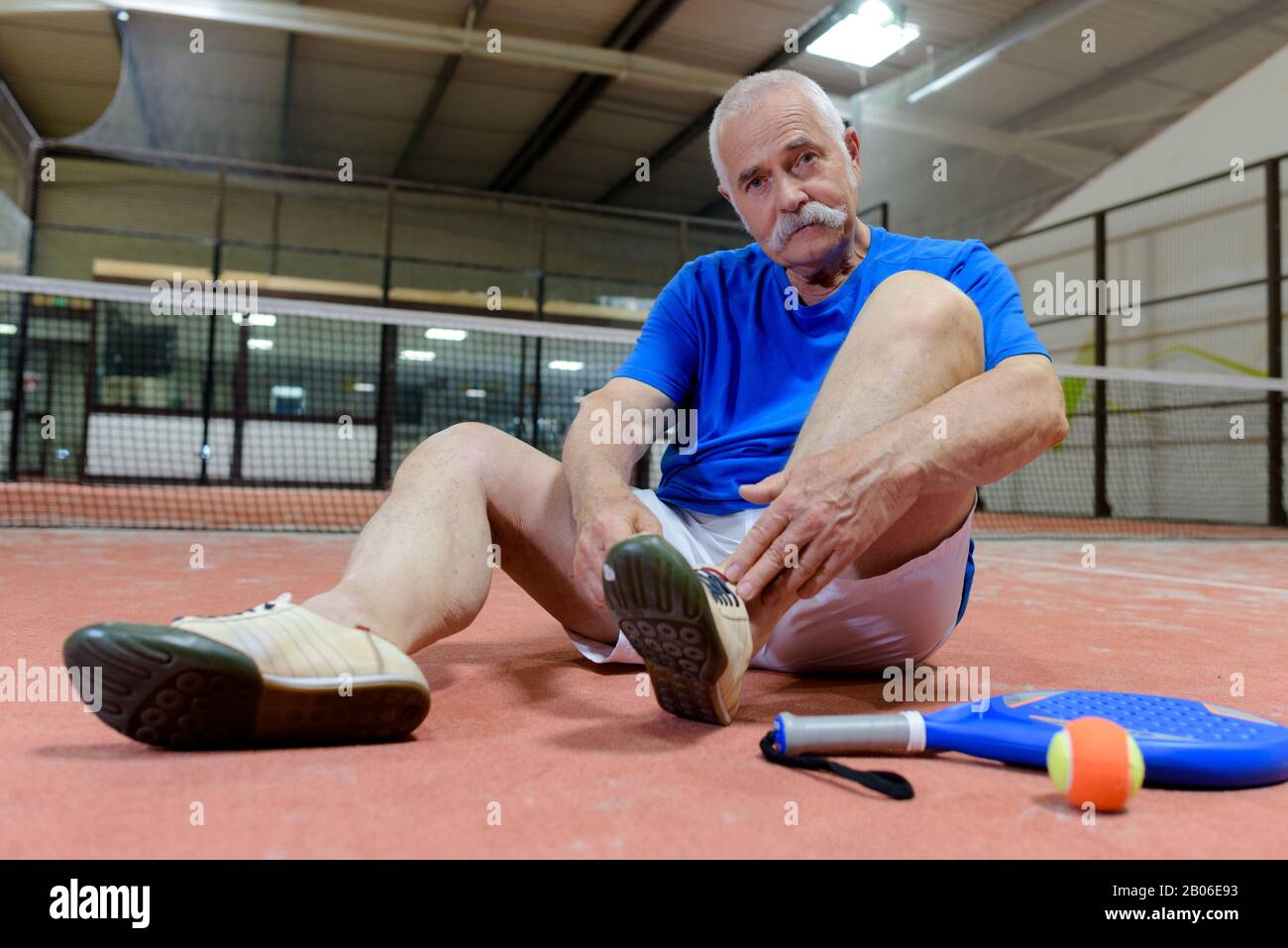 man removing his shoes for indoor beach tennis Stock Photo - Alamy