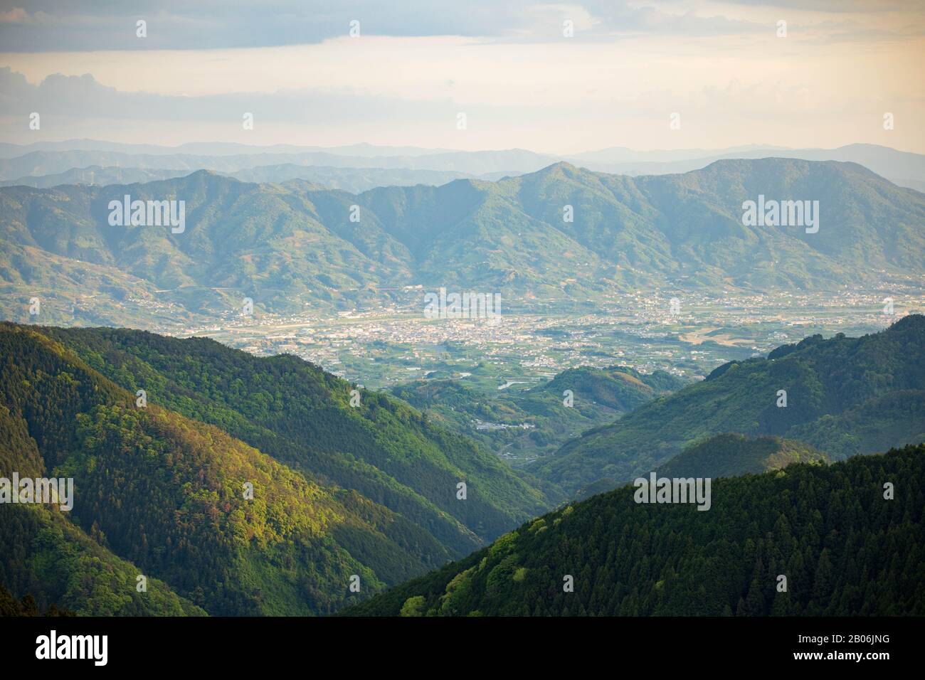 Small town nestled in valley between rugged green mountains Stock Photo ...