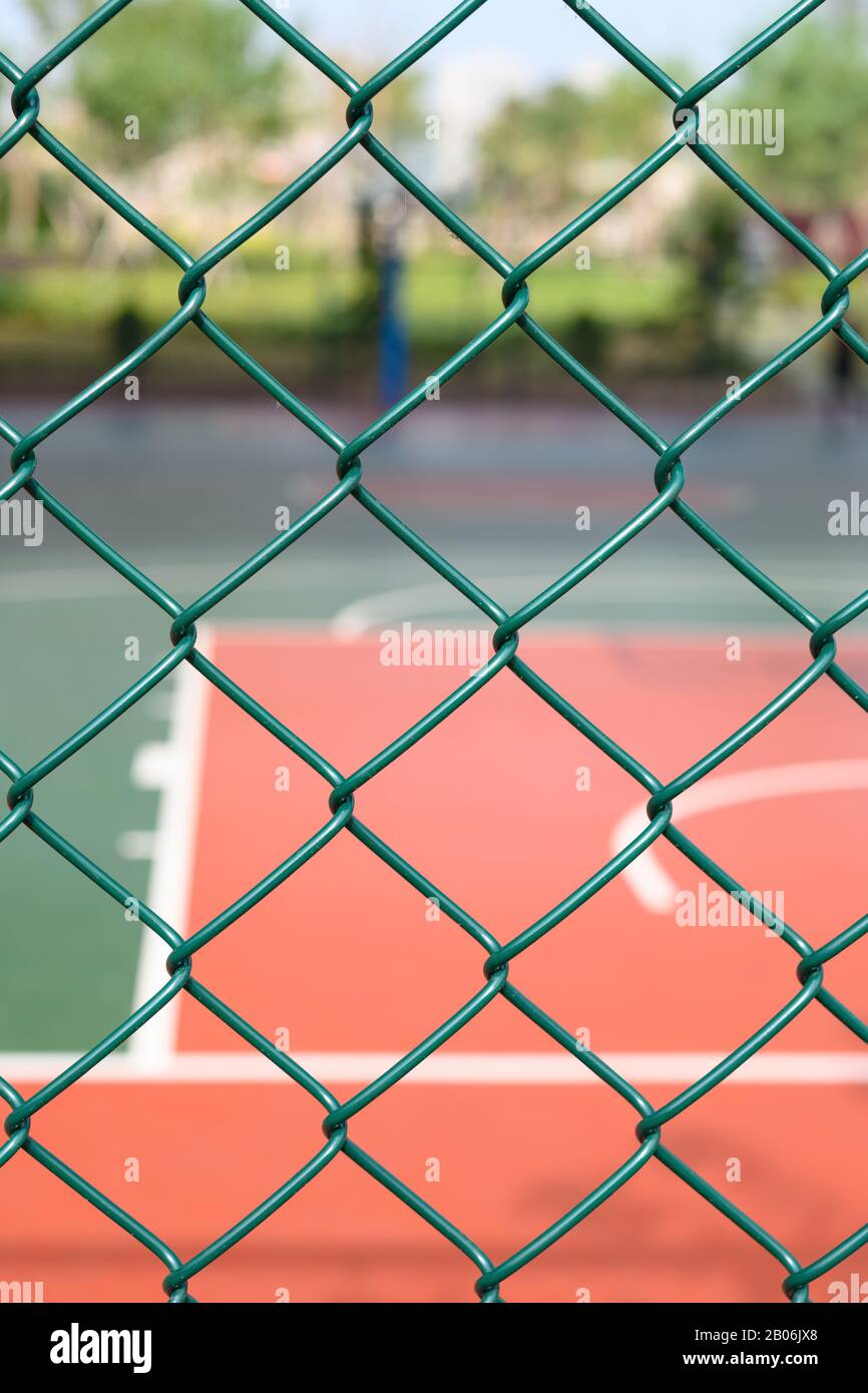 outdoor basketball court behind a metal fence vertical composition ...