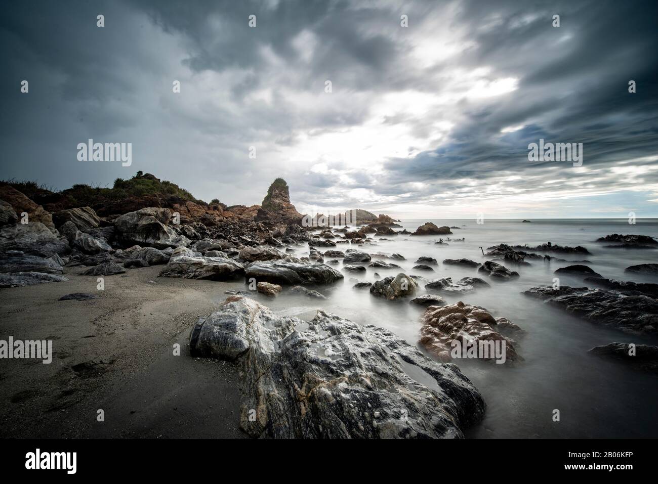 Rocky coast, rocks on the beach, dark rain clouds, long time exposure ...
