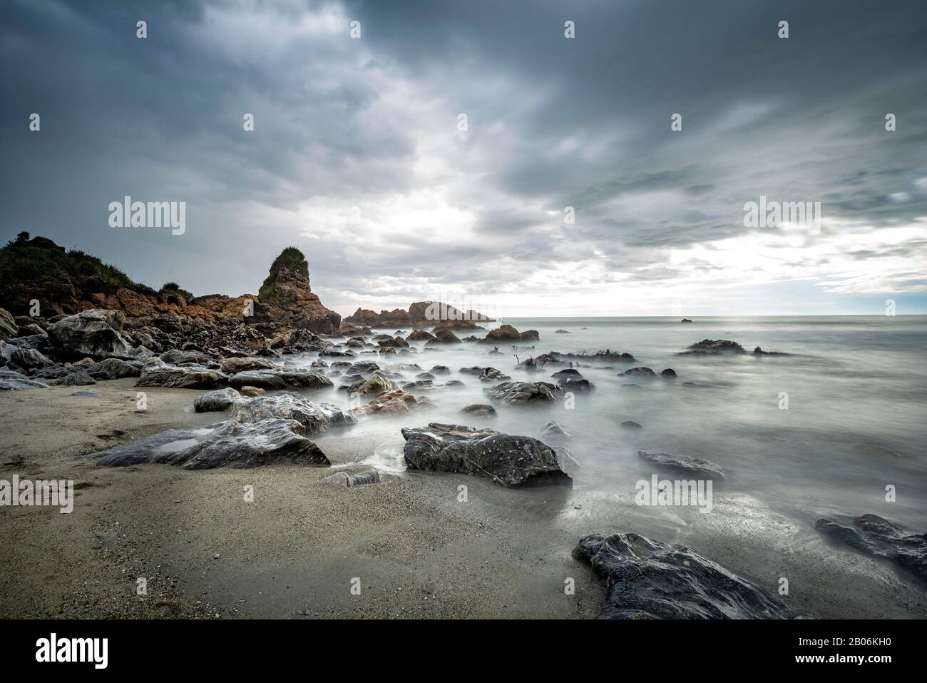 Rocky coast, rocks on the beach, dark rain clouds, long time exposure ...