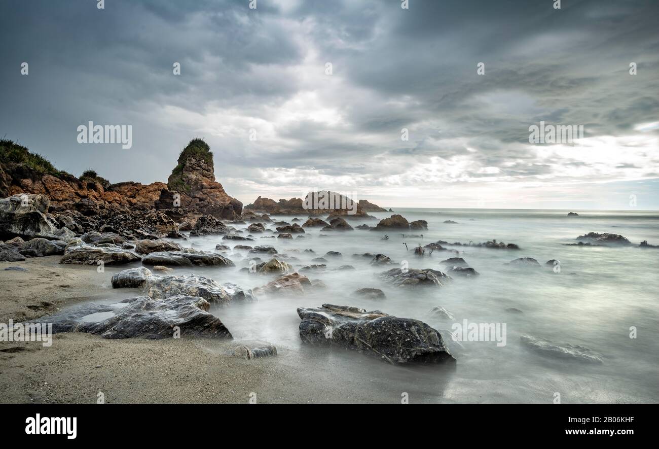 Rocky coast, rocks on the beach, dark rain clouds, long time exposure ...