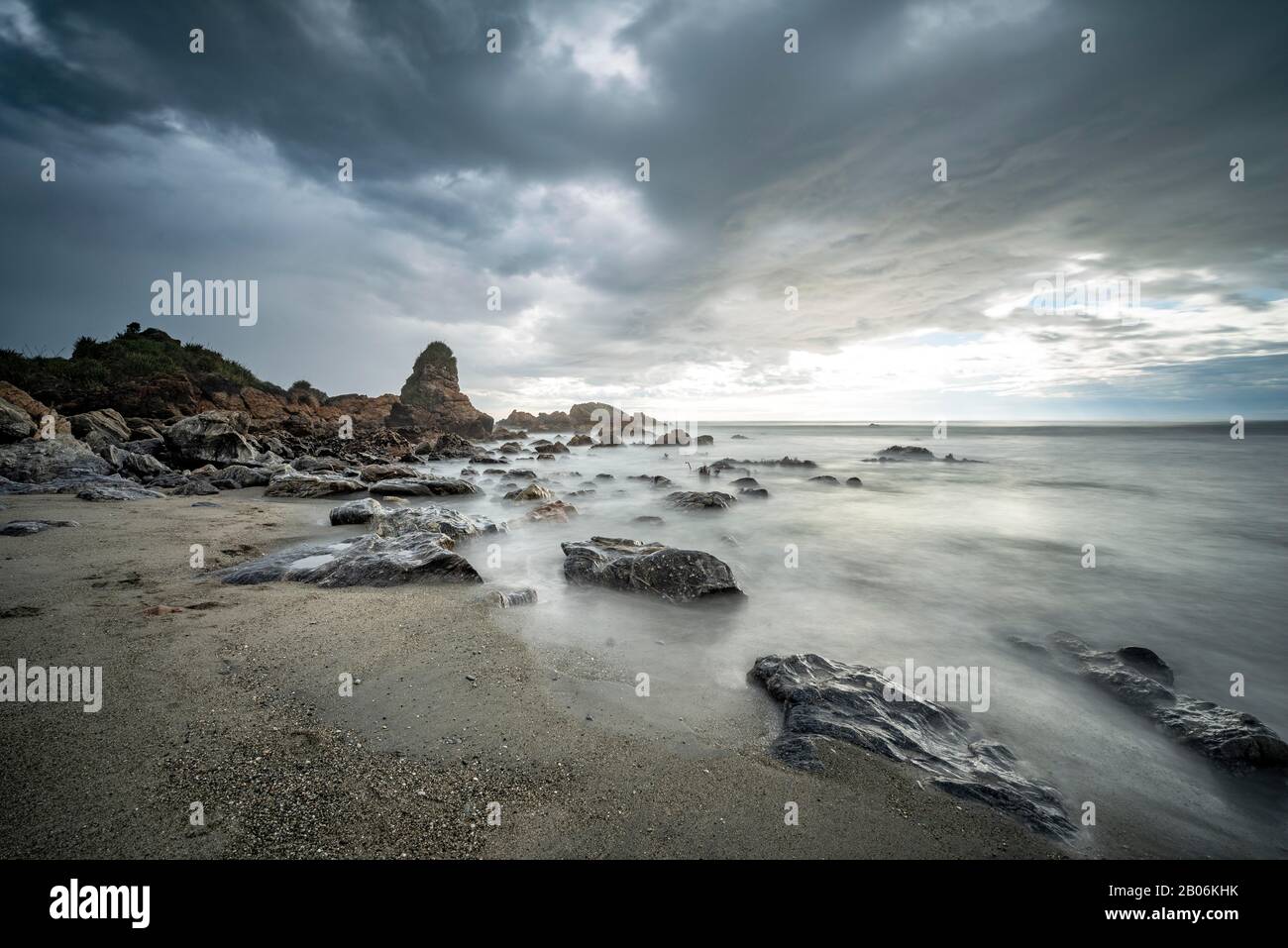 Rocky coast, rocks on the beach, dark rain clouds, long time exposure ...