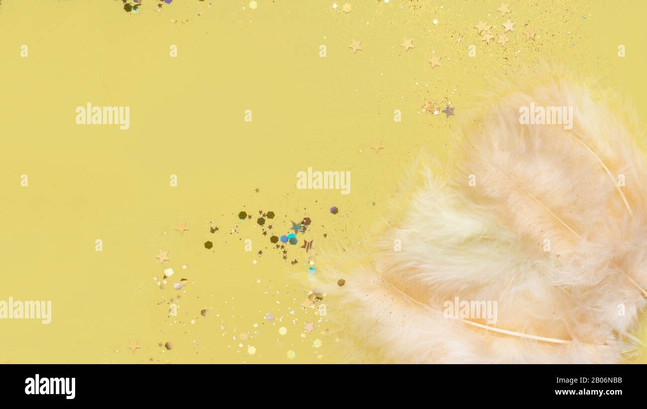Easter yellow festive background with beautiful feathers, glitters ...