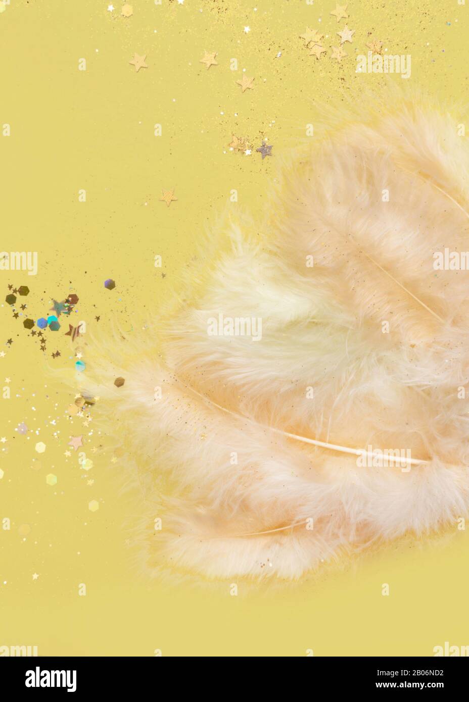 Easter yellow festive background with beautiful feathers, glitters ...