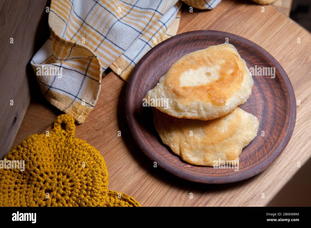 Clay plate with two of individual fried pies with meat on wooden table ...