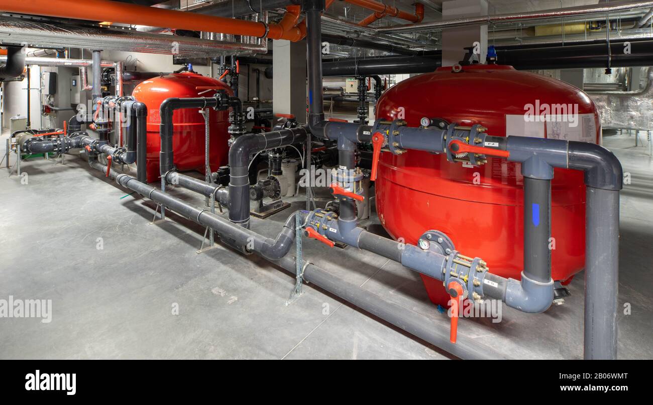 Interior of modern boiler room. Piping system. Large red boiler units ...
