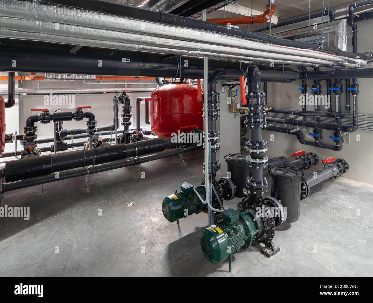 Interior of modern boiler room. Piping system. Large red boiler unit ...