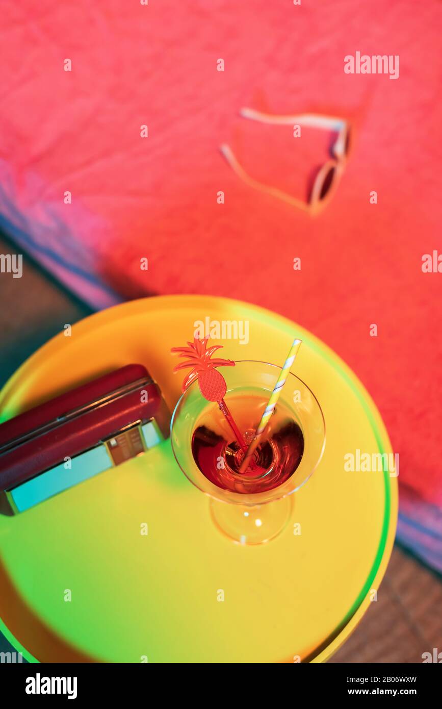 Cocktail beverage and vintage radio on yellow table next to sunbed ...