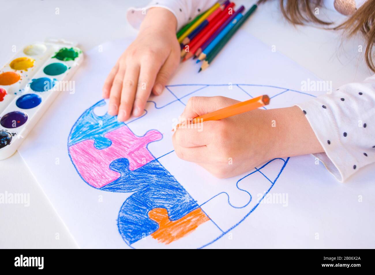 A child is drawing colorful heart with jigsaw puzzle on white ...